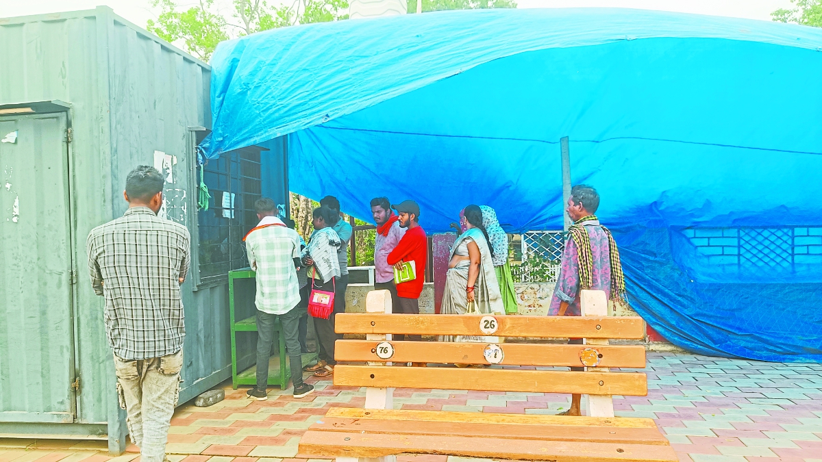 रेलवे स्टेशन में तिरपाल के नीचे खड़े होकर यात्री खरीद रहे टिकट ...